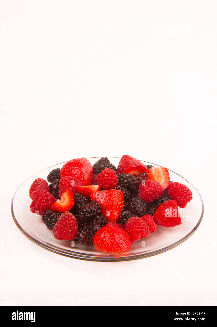 A pile of mixed berries on a glass plate on a white background Stock ...
