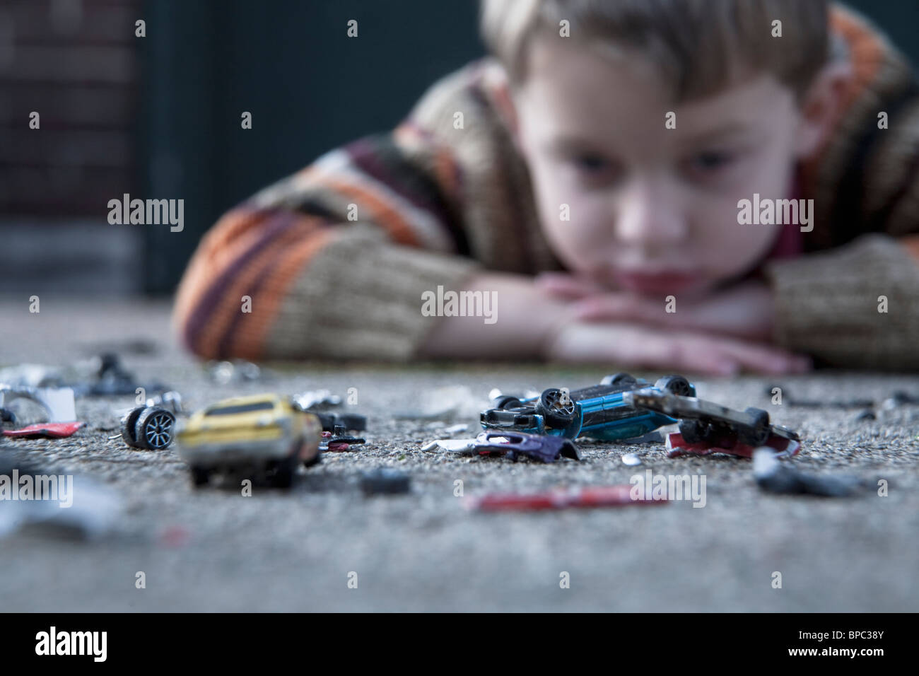 Boy in background of smashed toy cars. Shallow depth of field / select ...