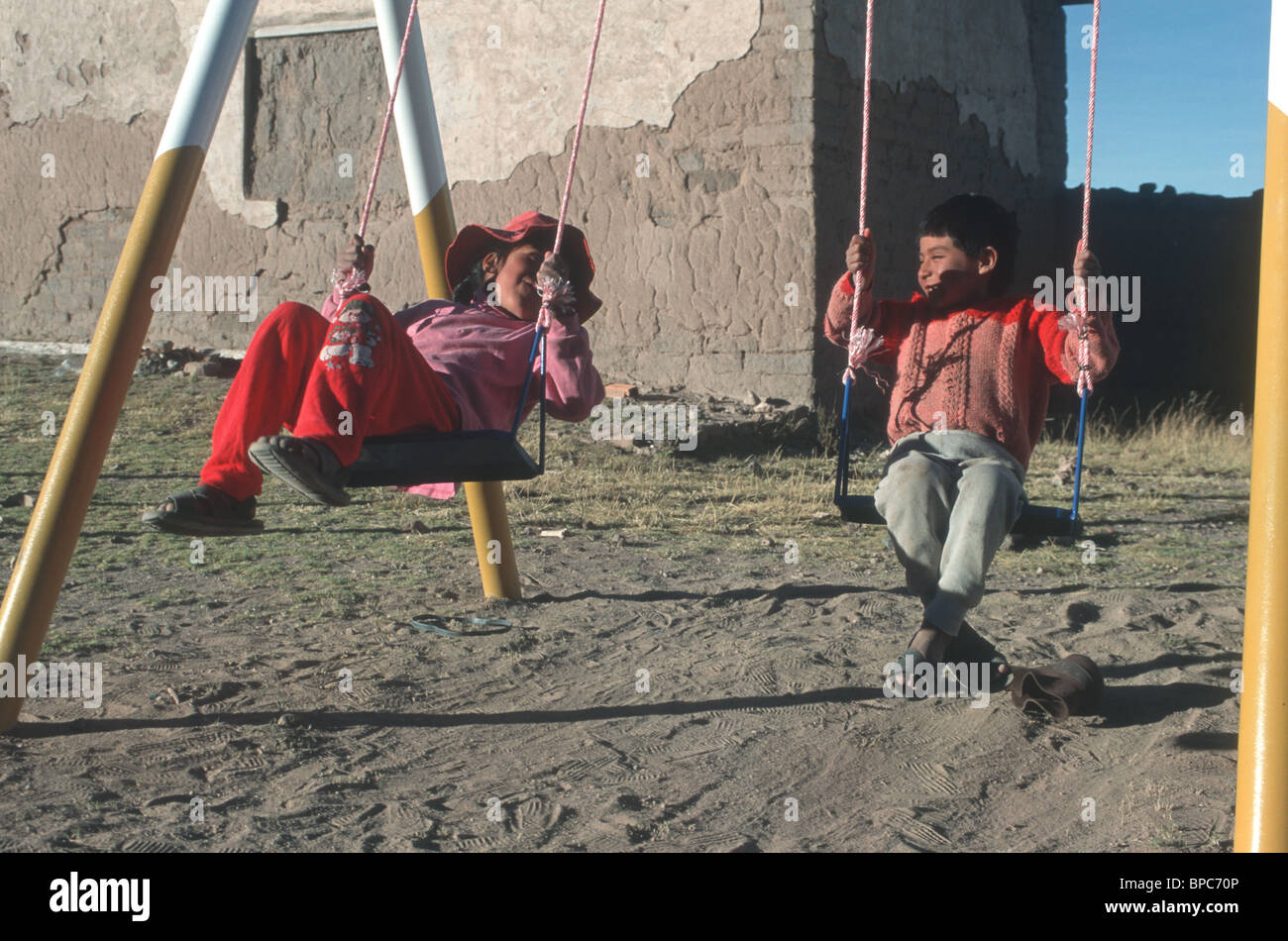 BOLIVIA NATIVE AYMARA CHILDREN PLAYING IN SWINGS IN THE ANDEAN REGION ...