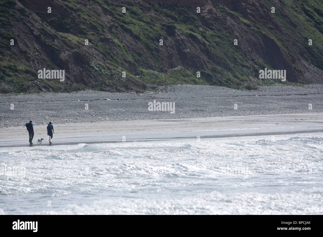 People walking along beach Stock Photo - Alamy