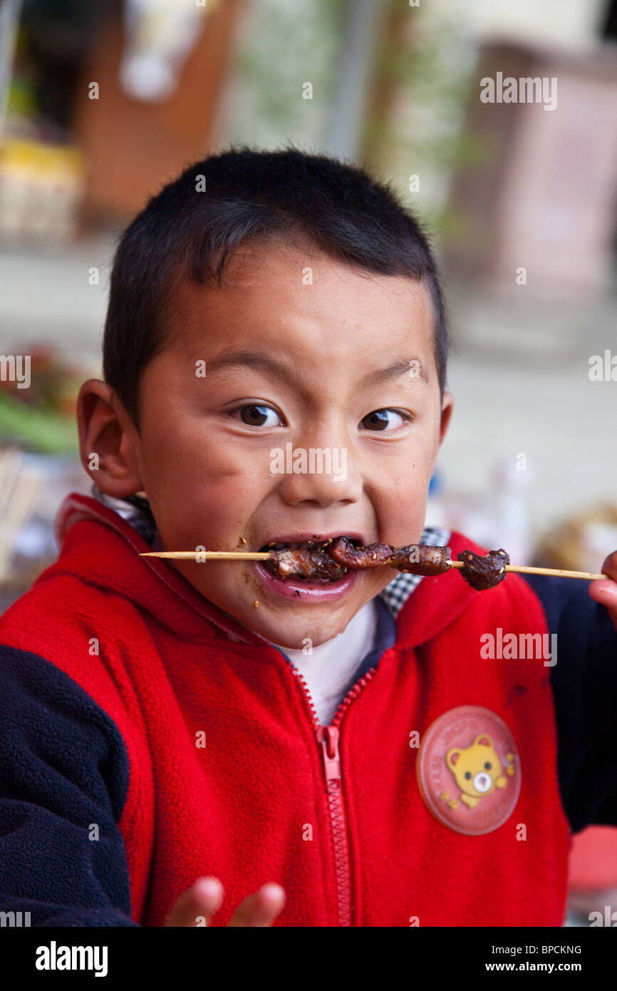 Boy eating street food in Shangri-La or Zhongdian in Yunnan Province ...