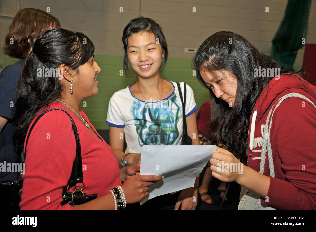 A smiling GCSE student with her freinds looking happy with her exam ...