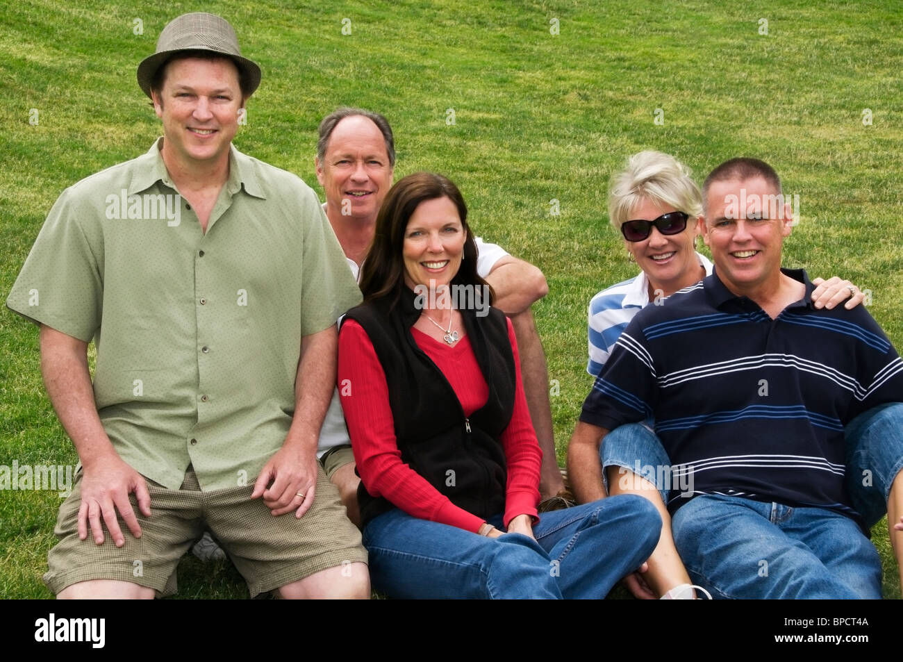 Siblings and spouses gather for a summer family reunion outdoors in a ...