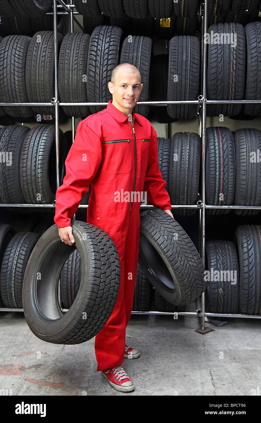 A motivated worker in a tire workshop carrying two tires Stock Photo ...