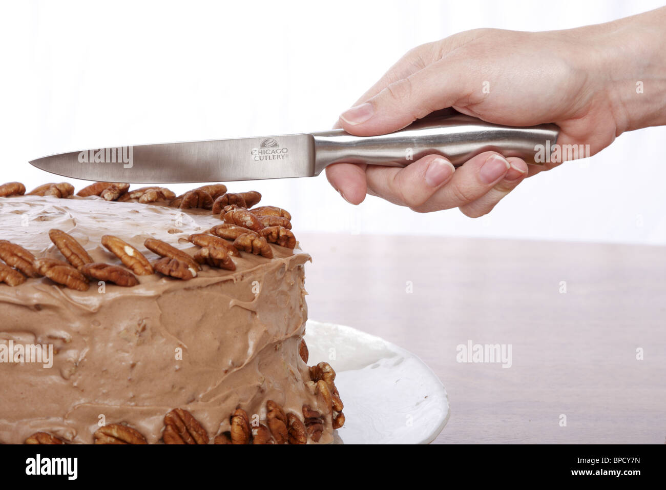 Hand about to cut into cake Stock Photo - Alamy