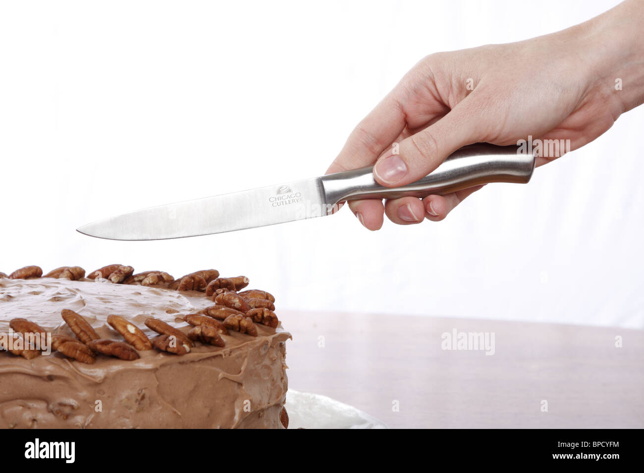 Hand about to cut into cake Stock Photo - Alamy