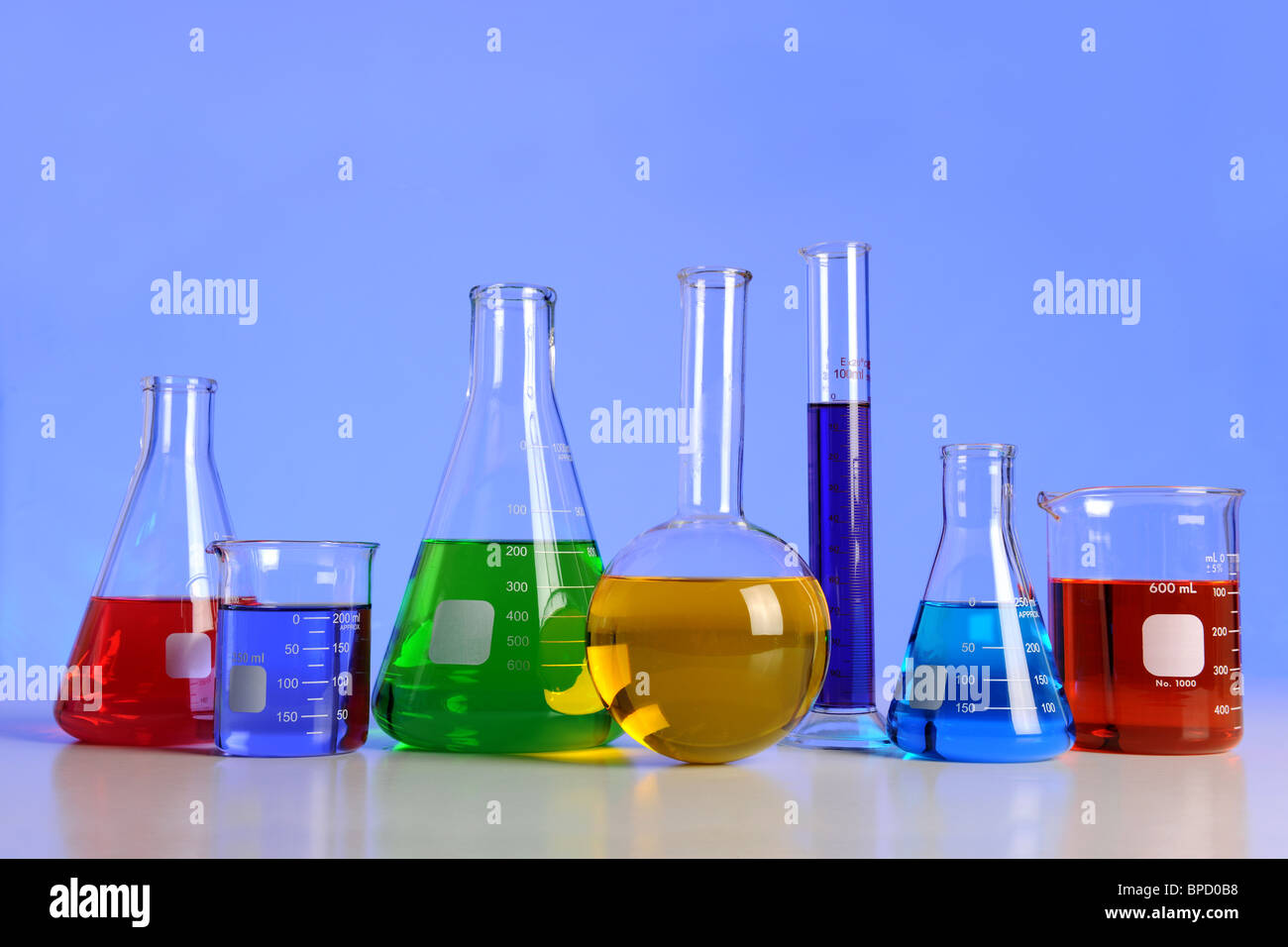 Laboratory glassware over blue background with reflections on table ...
