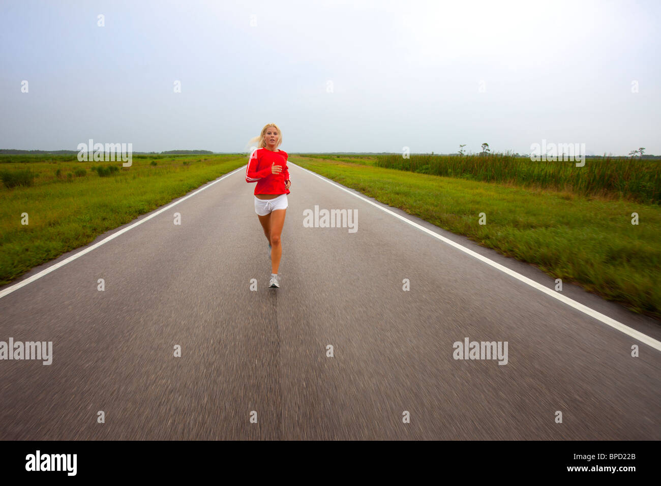 Young woman jogging on country road Stock Photo - Alamy