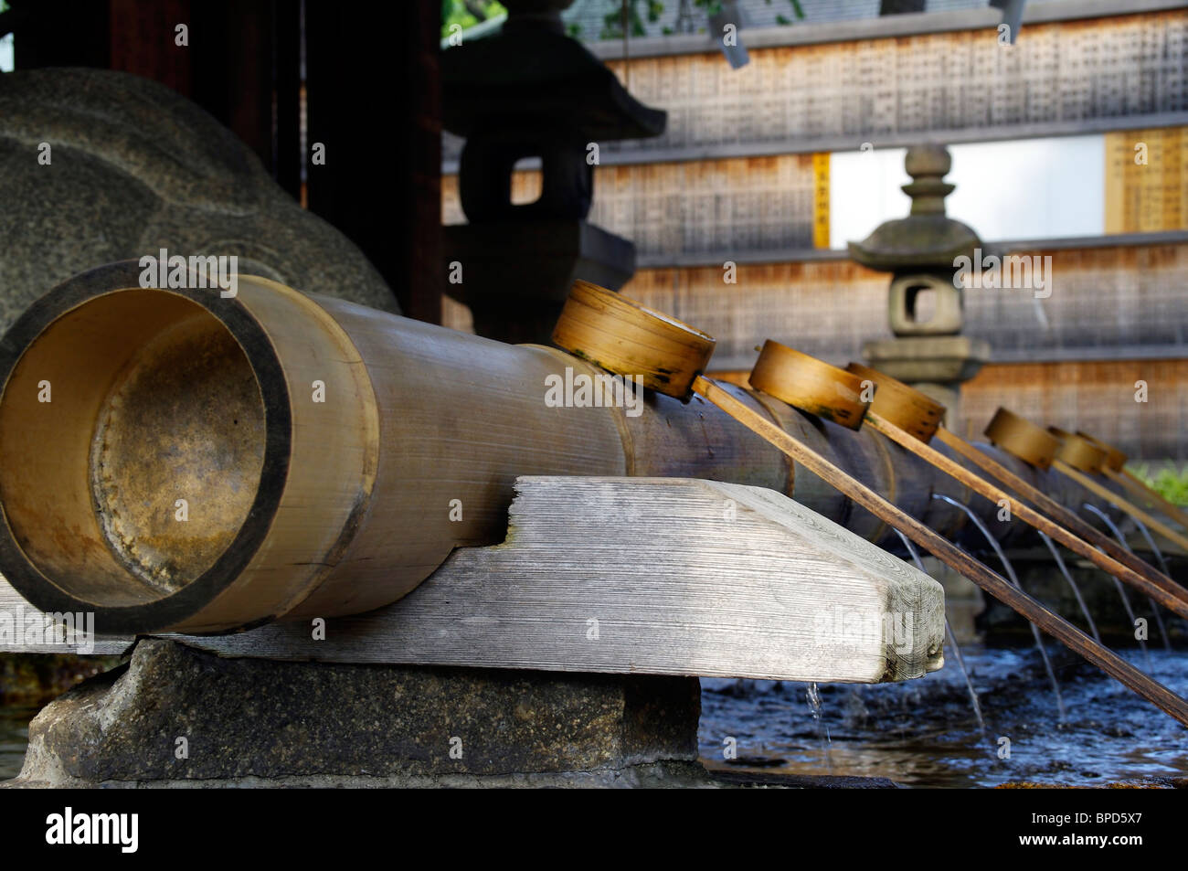 A purification basin with ladles in front of a Japanese Shinto shrine ...