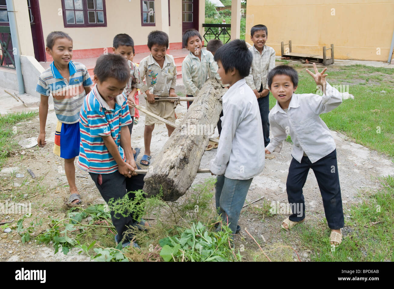School children carrying a large tree stump or log from their new ...