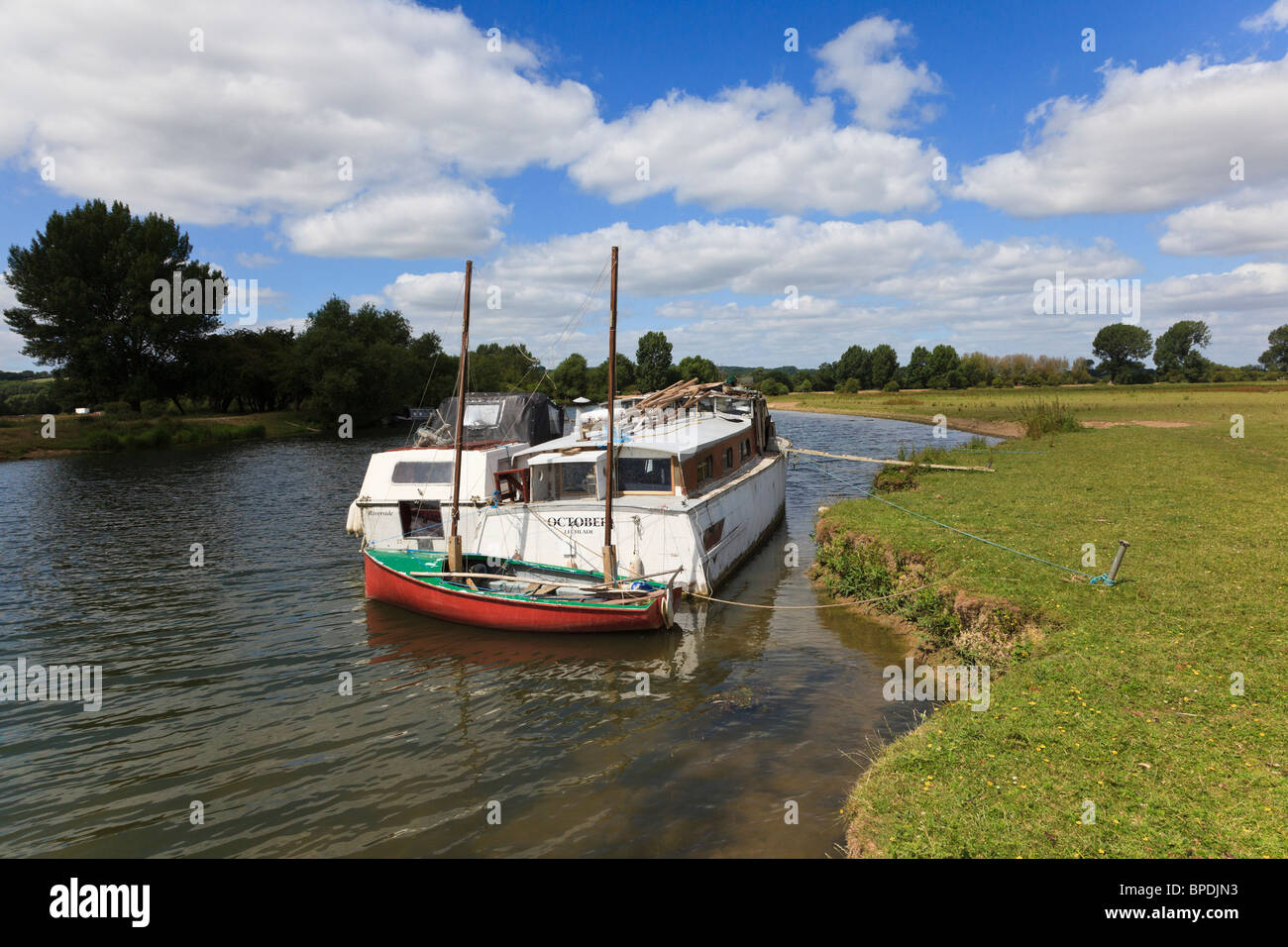 Traditional sailing dinghy moored to houseboats on the River Thames or ...