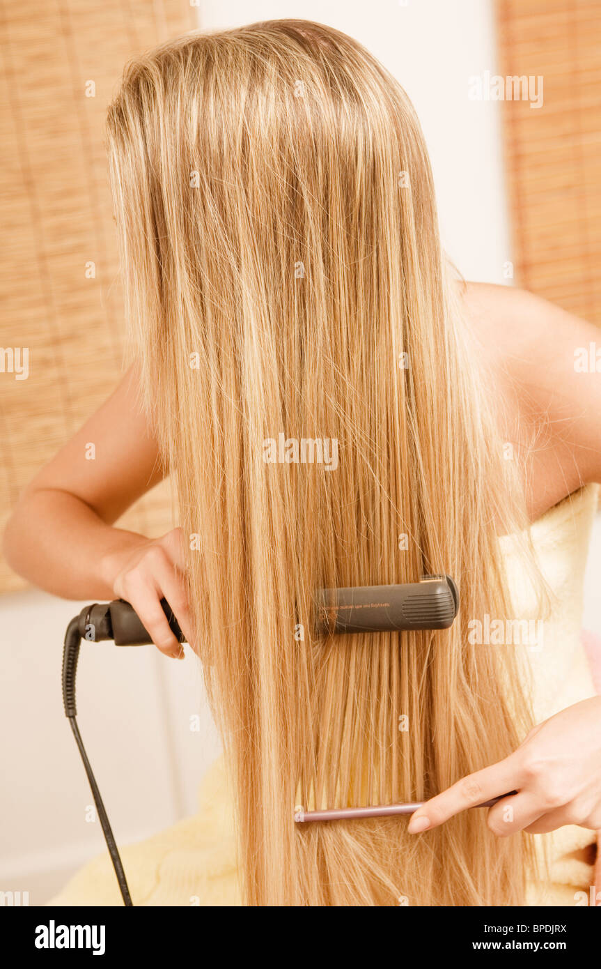 Getting ready for a night out, straightening hair Stock Photo - Alamy