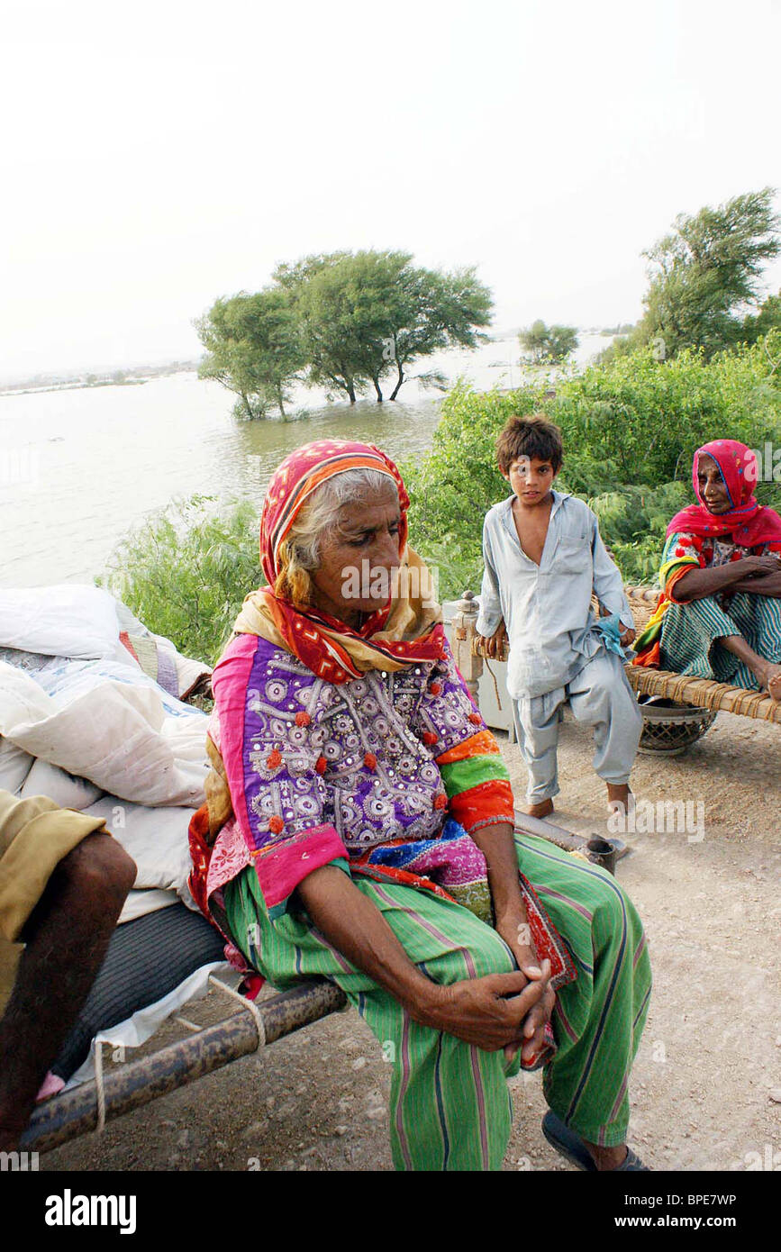 Flood affected women sit with their household under the open sky as ...