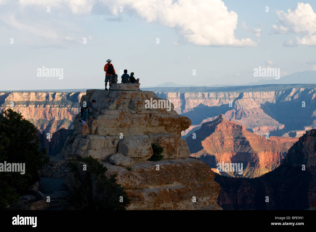 Tourists at bright angel point view perched on rocks overlooking the ...