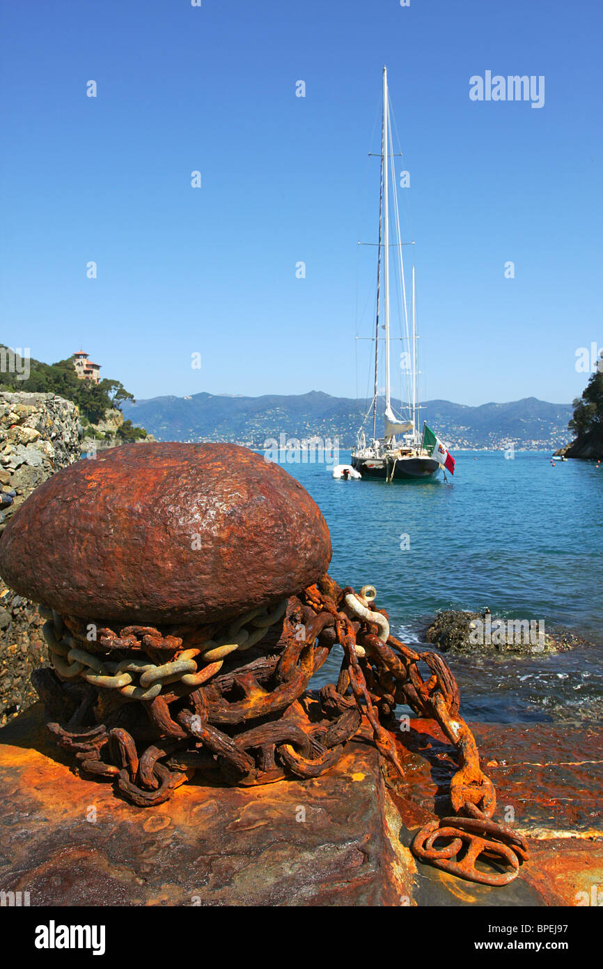 Vertical oriented image of old rusty chain on the pier and yacht on the ...
