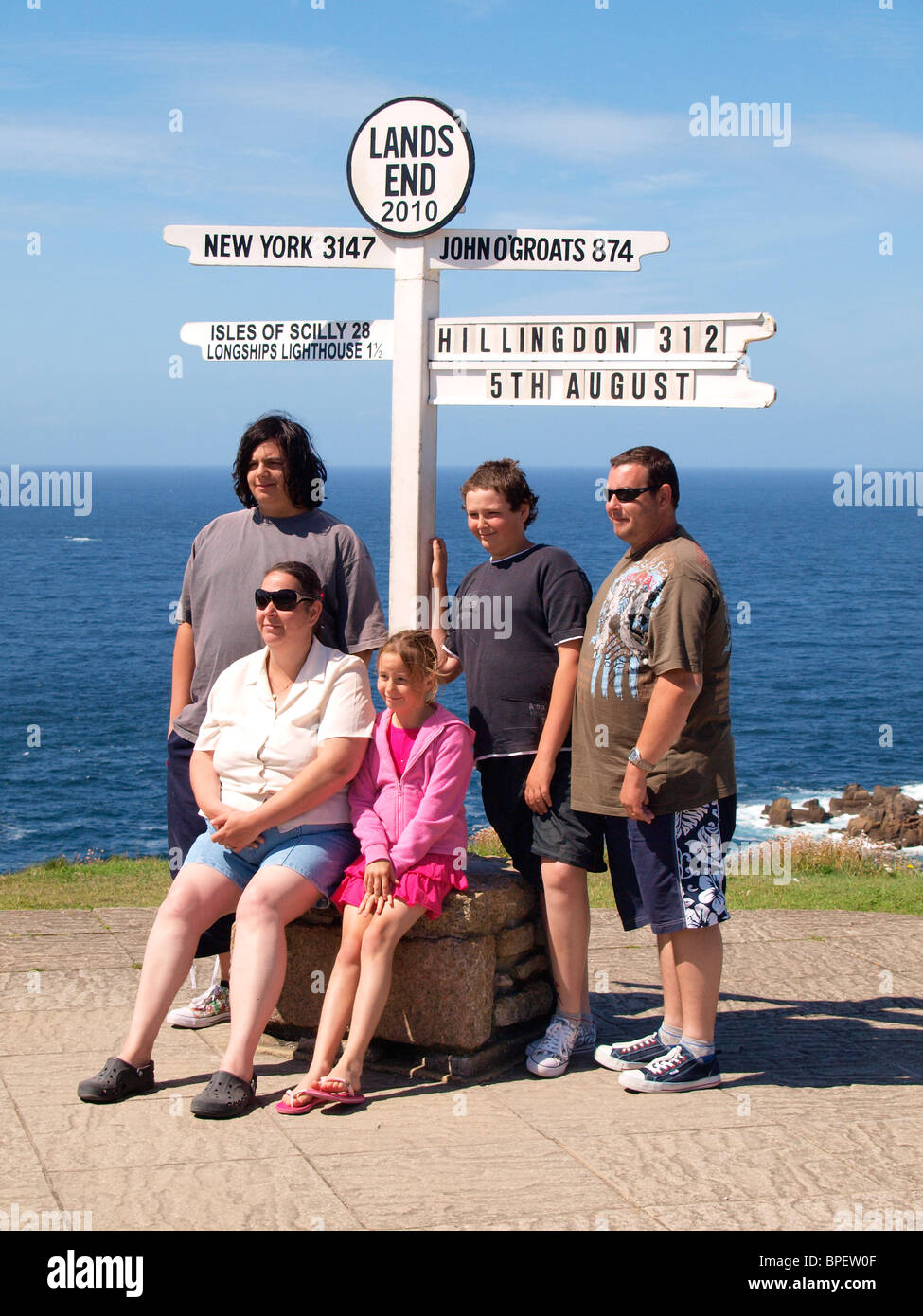 Family having picture taken in front of sign post at Land's End ...