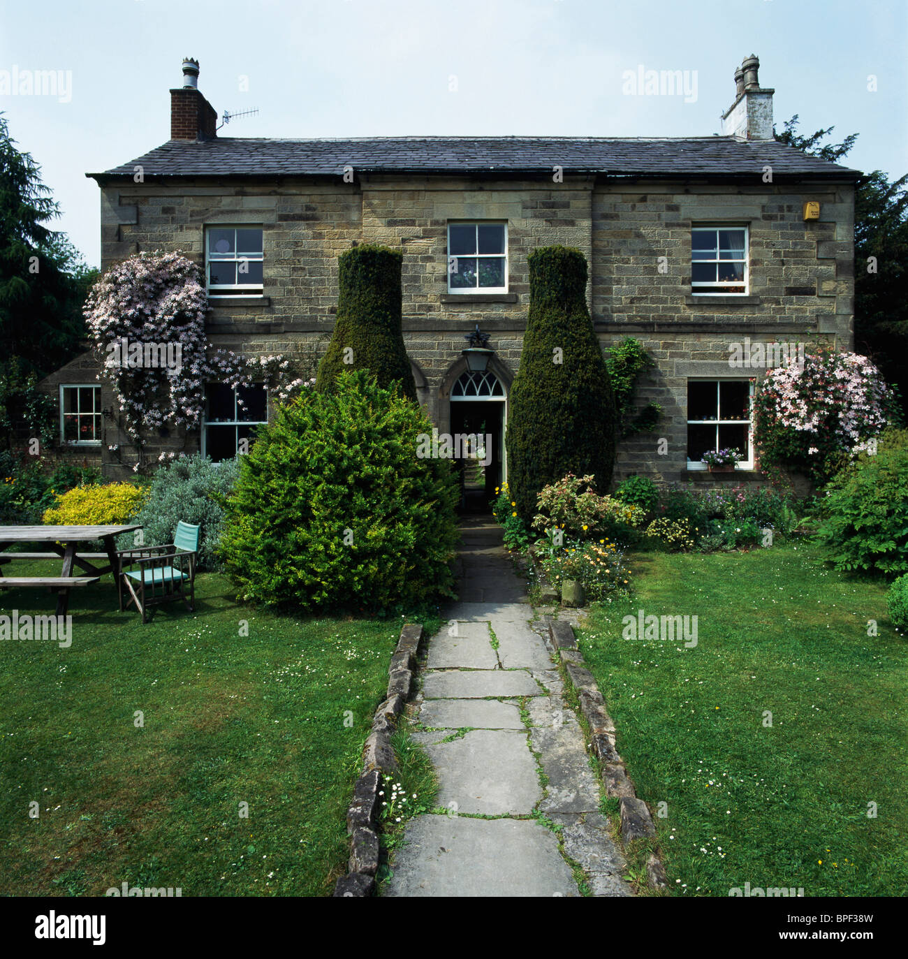 Lawns on either side of stone paved path leading to stone-built country ...