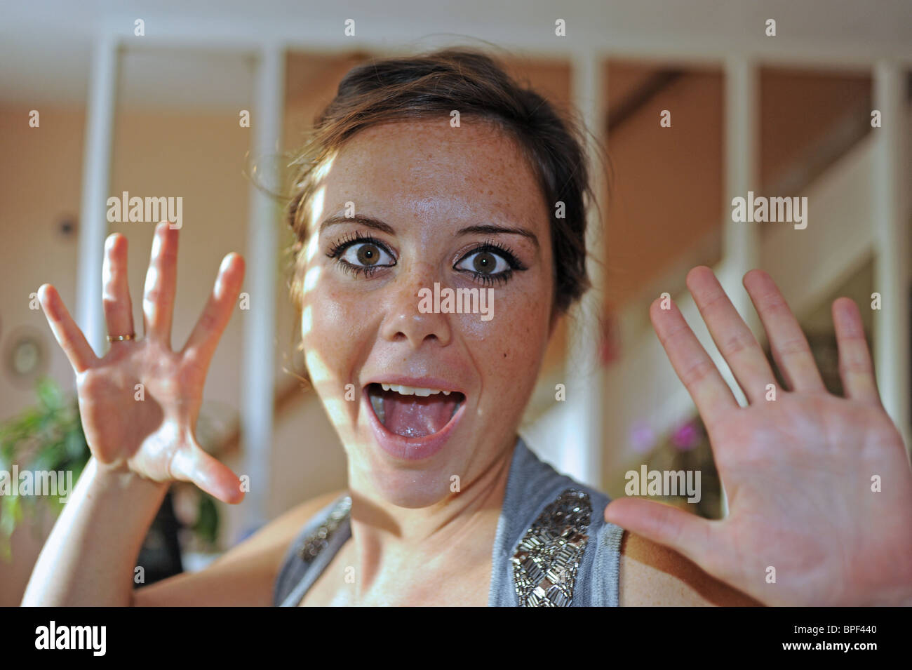 Young attractive woman making fun face with mouth open wide into camera ...
