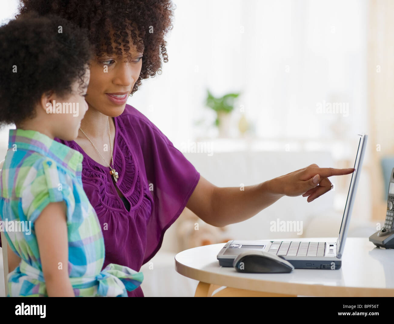 Mother pointing to laptop with daughter Stock Photo - Alamy