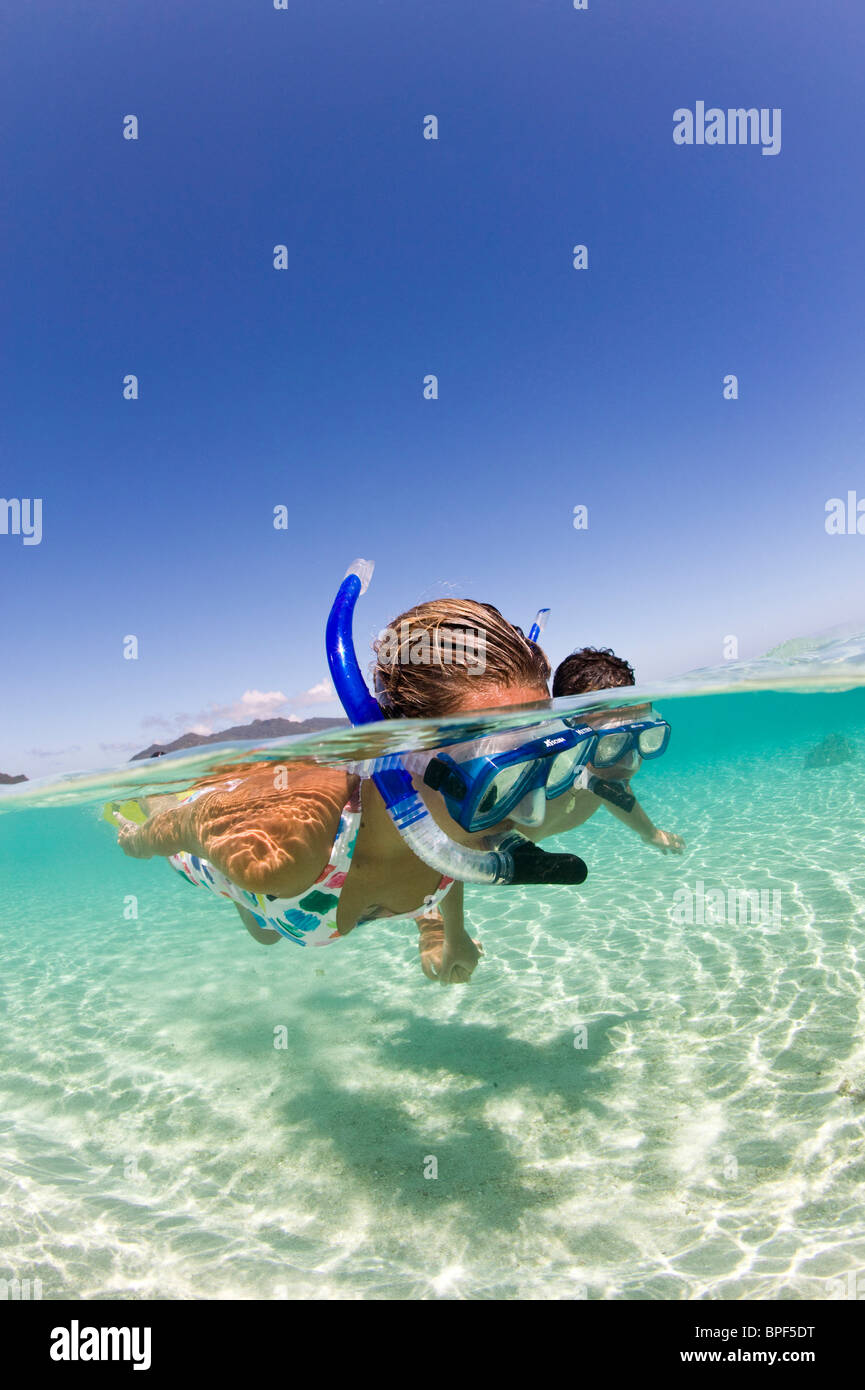 couple enjoying snorkeling the clear tropical waters of a remote island ...