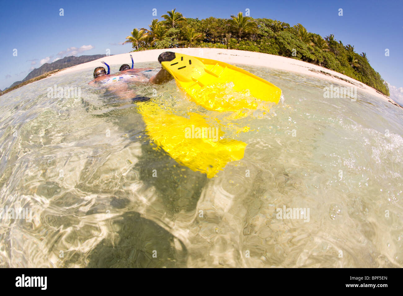 couple enjoying snorkeling the clear tropical waters of a remote island ...