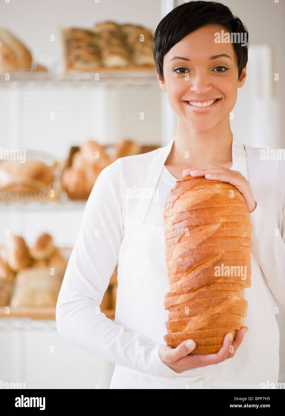 Mixed race woman in bakery holding bread Stock Photo - Alamy