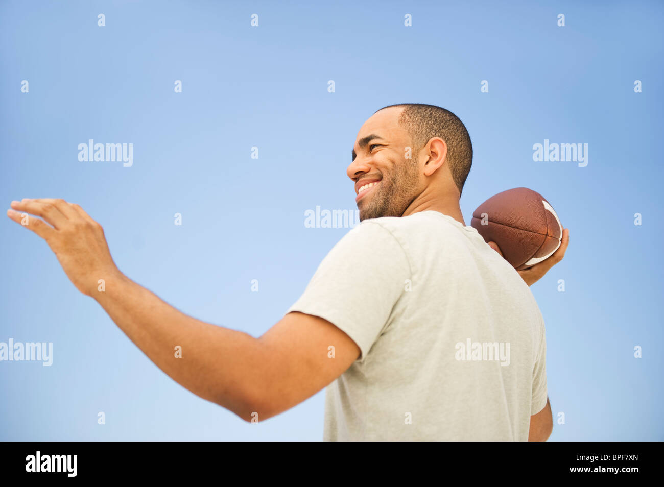 Mixed race man throwing football Stock Photo - Alamy