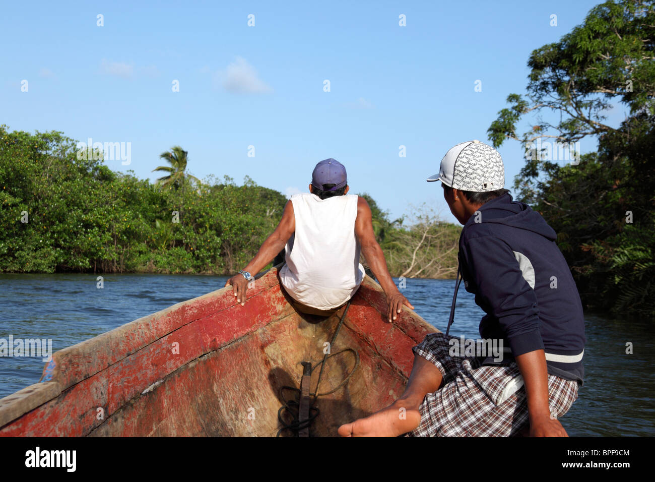 Kuna indigenous boys sitting on prow of a traditional dugout wooden ...
