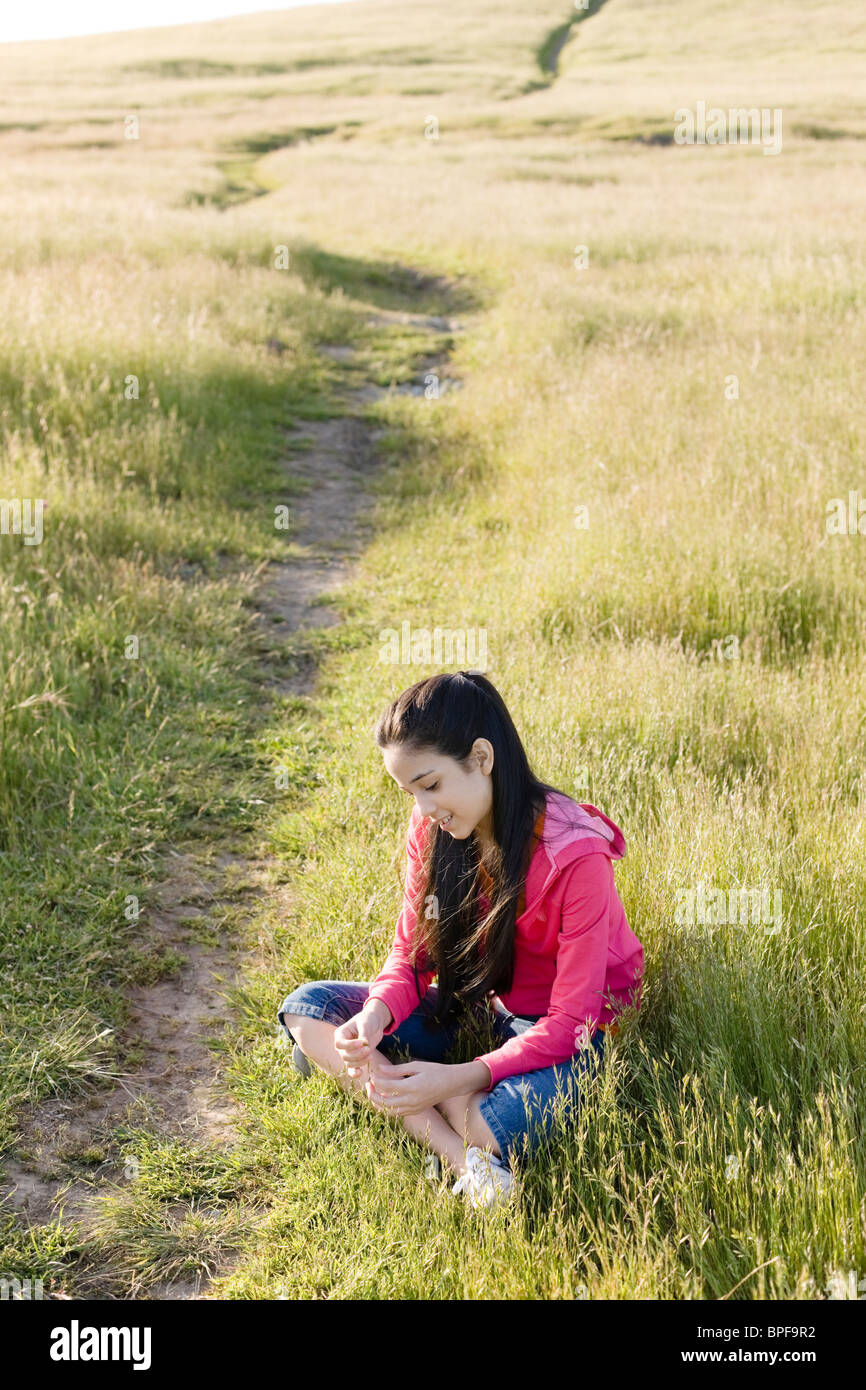 Hispanic girl sitting in field Stock Photo - Alamy