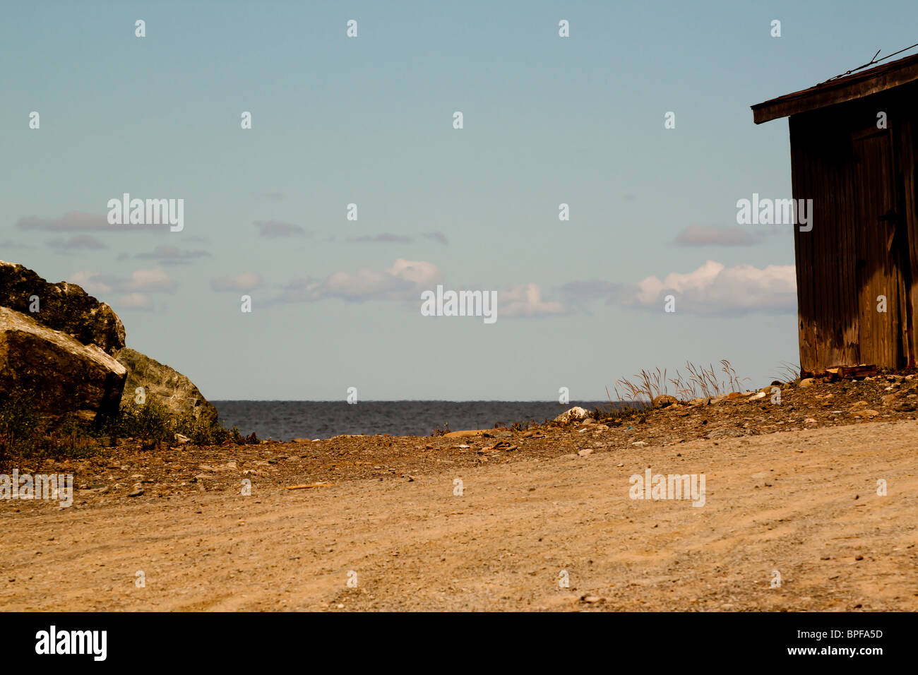 A small wooden shack and a rock frame the ocean Stock Photo - Alamy