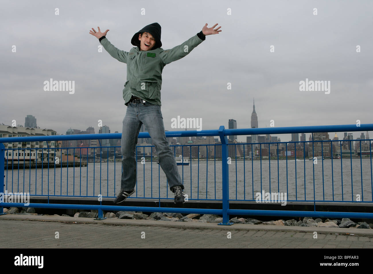 Happy Chinese man jumping on bridge Stock Photo - Alamy