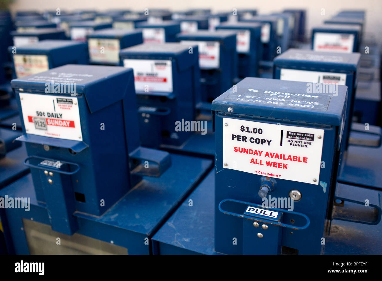 Rows of surplus newspaper boxes sit in an alley behind a building in ...