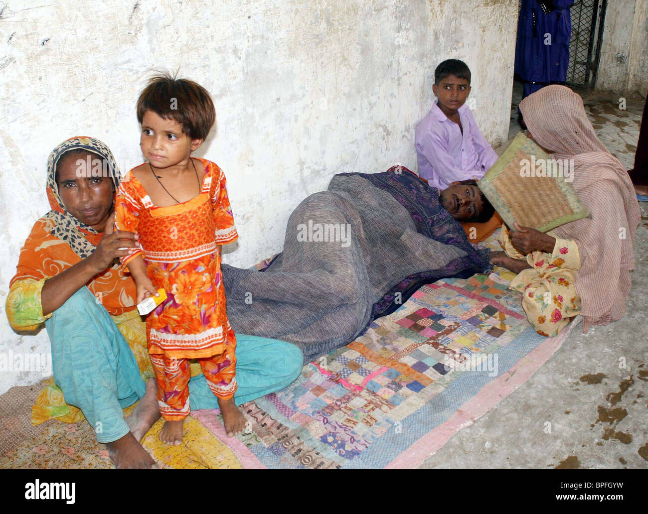 Flood affected women sit with their sick relative on floor at flood ...