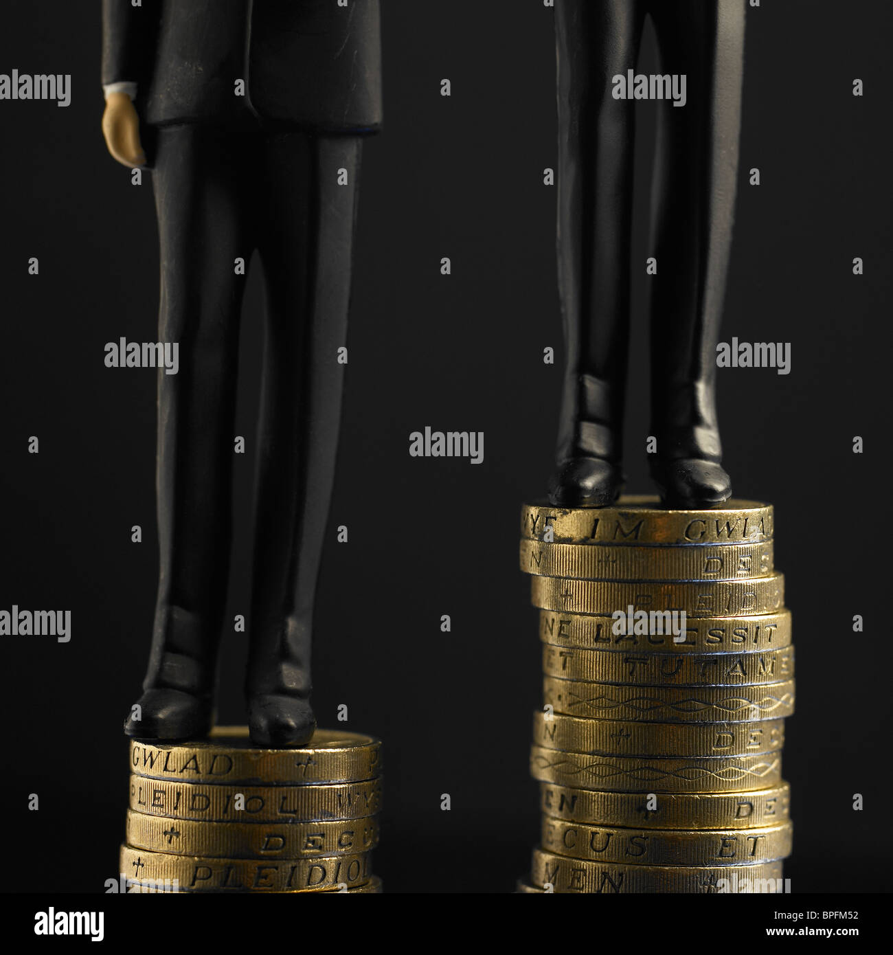 Two Figures In Black Suits Standing On Top Of Two Piles Of Pound ...
