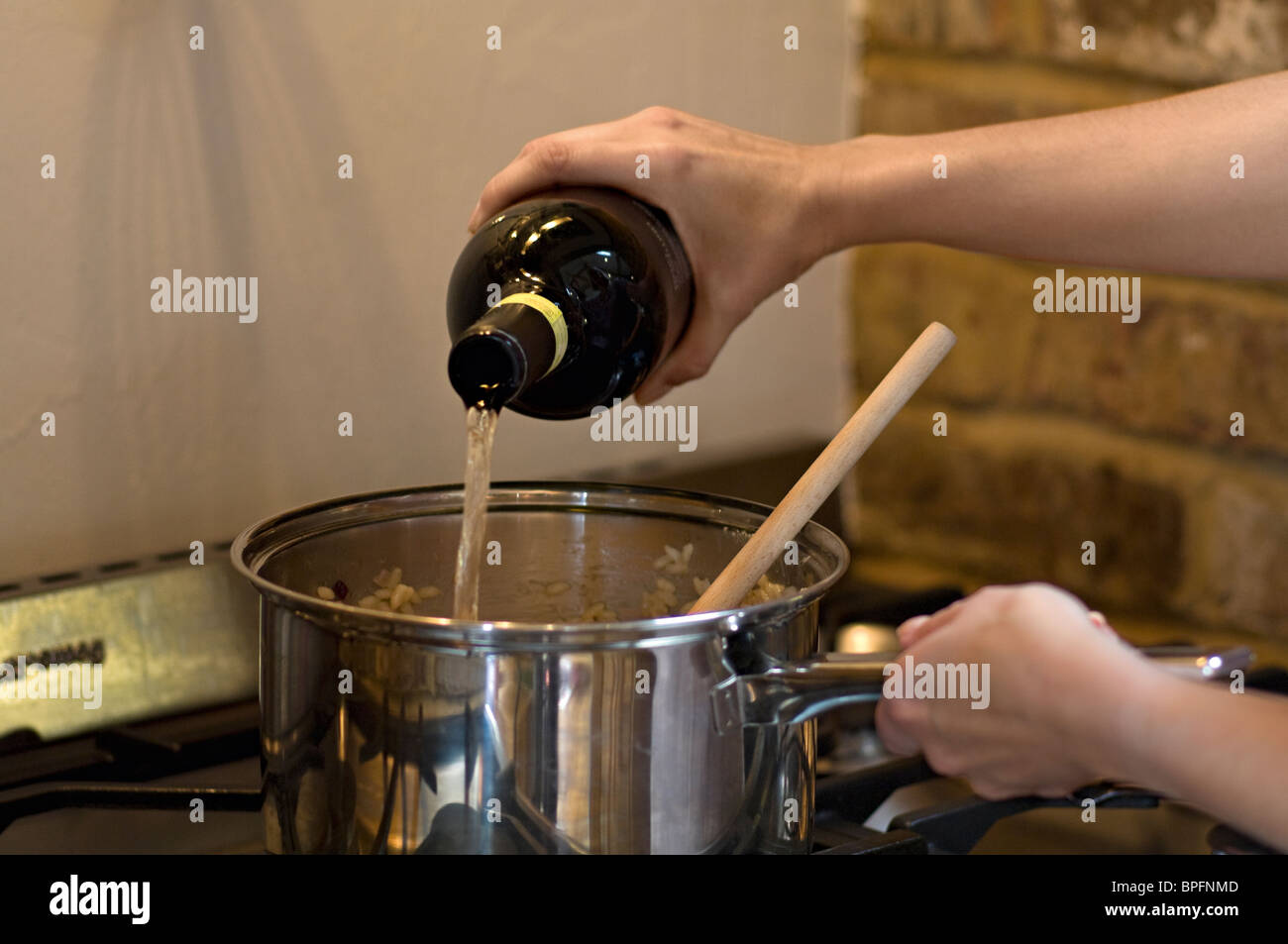Adding wine to a rice dish cooking on the stove Stock Photo - Alamy