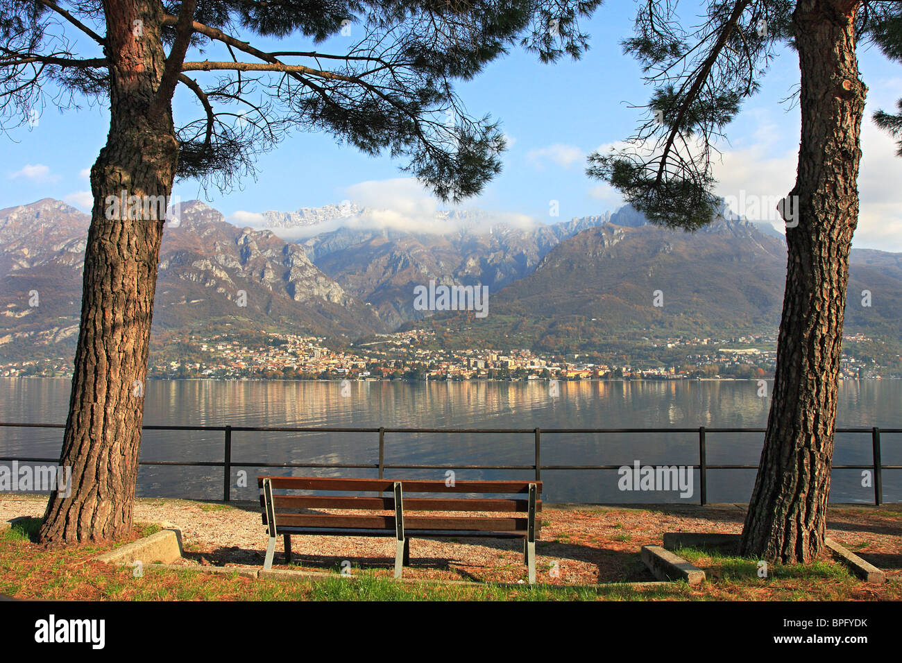 Bench between two trees on the promenade along the mountains and Lake ...