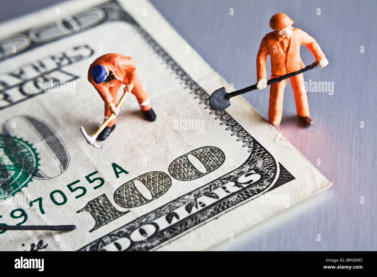 Worker figurines placed on a 100 dollar bill Stock Photo - Alamy
