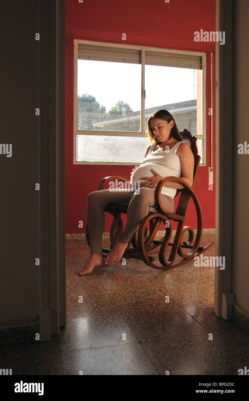 Pregnant woman at home, sitting in a rocking chair by the window Stock ...