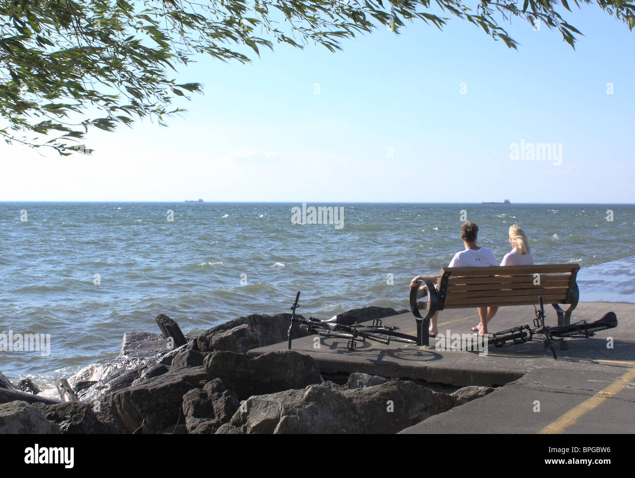 young couple sitting on bench watching the lake after a bike ride Stock ...
