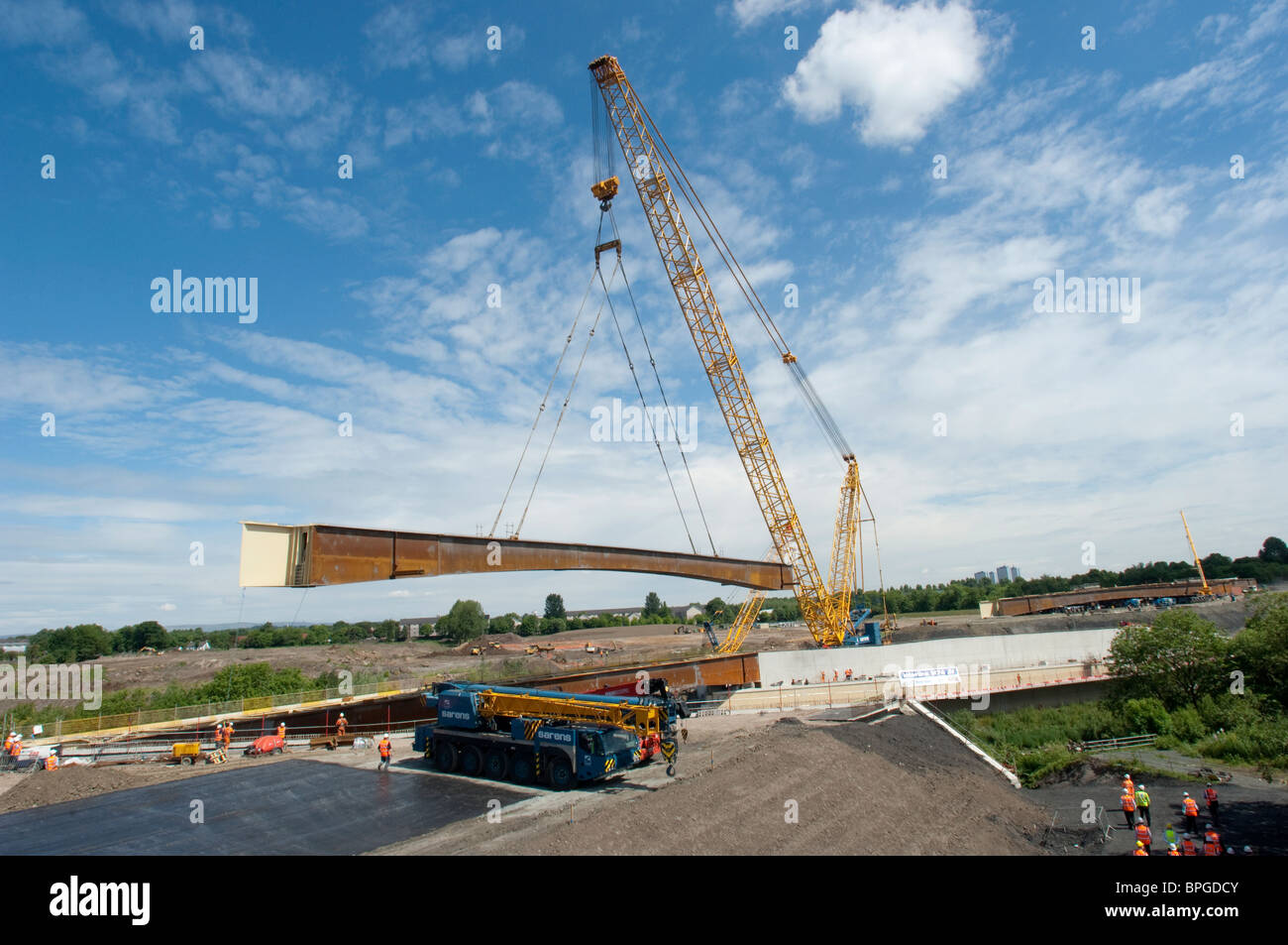 Construction workers move a steel bridge by crane into position over ...