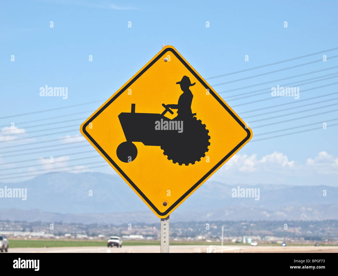Farm tractor crossing caution sign with fields and encroaching suburbia ...