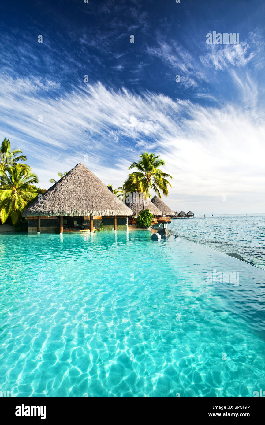 Infinity pool with artificial beach and tropical ocean Stock Photo - Alamy