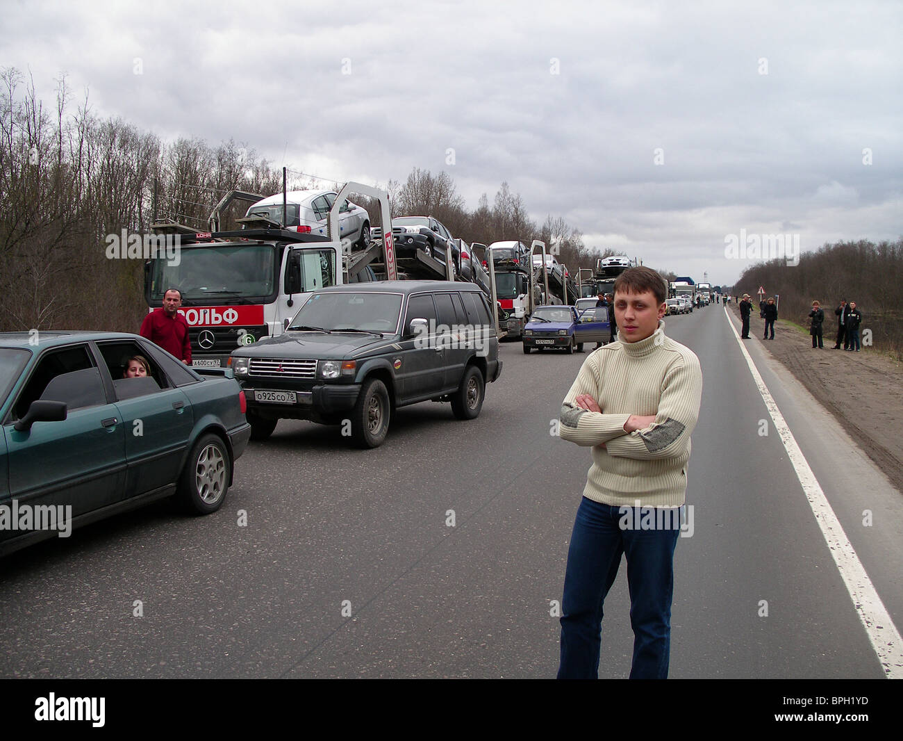 A crowd of people waiting out of the car on a suburban road in the ...
