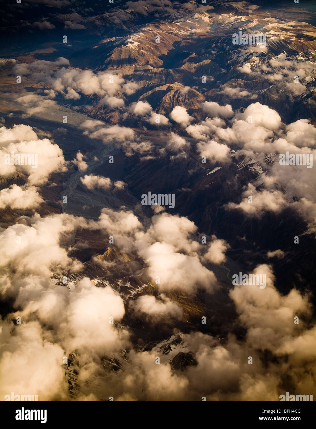 Aerial view of mountain range with snow capped peaks in late afternoon ...