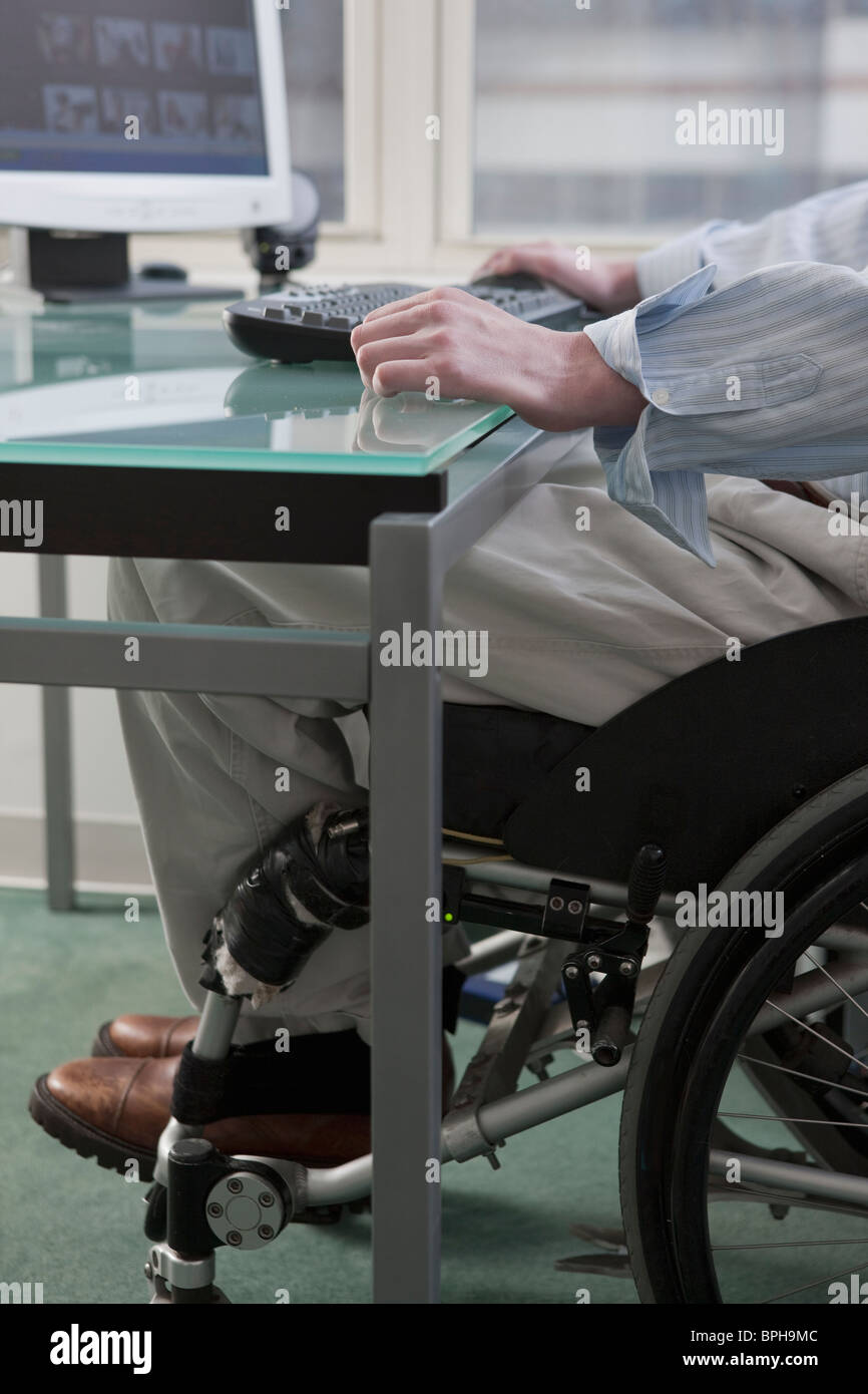 Man in a wheelchair working at desk in a home office Stock Photo - Alamy