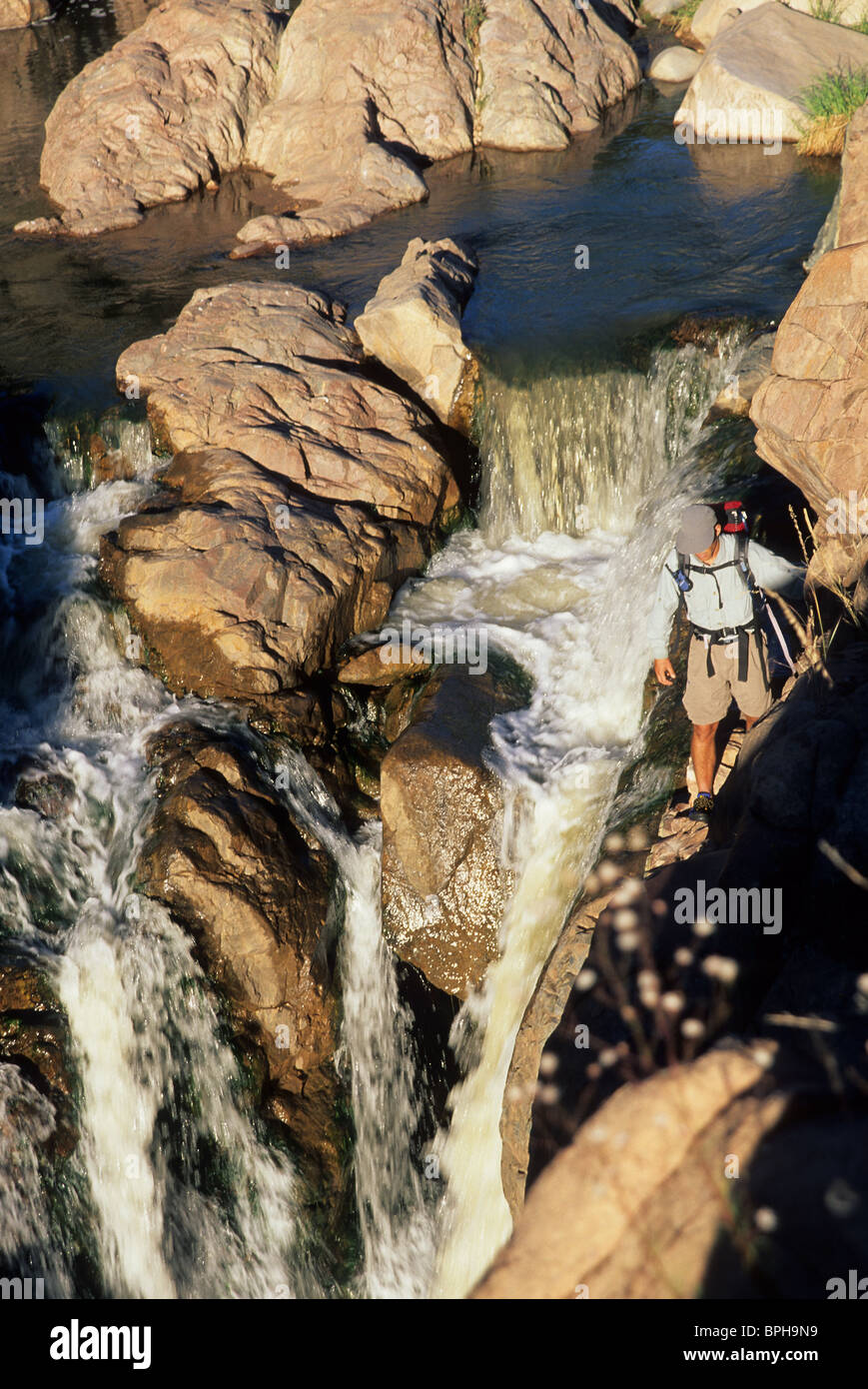 Man looking over cliff to waterfalls Stock Photo - Alamy