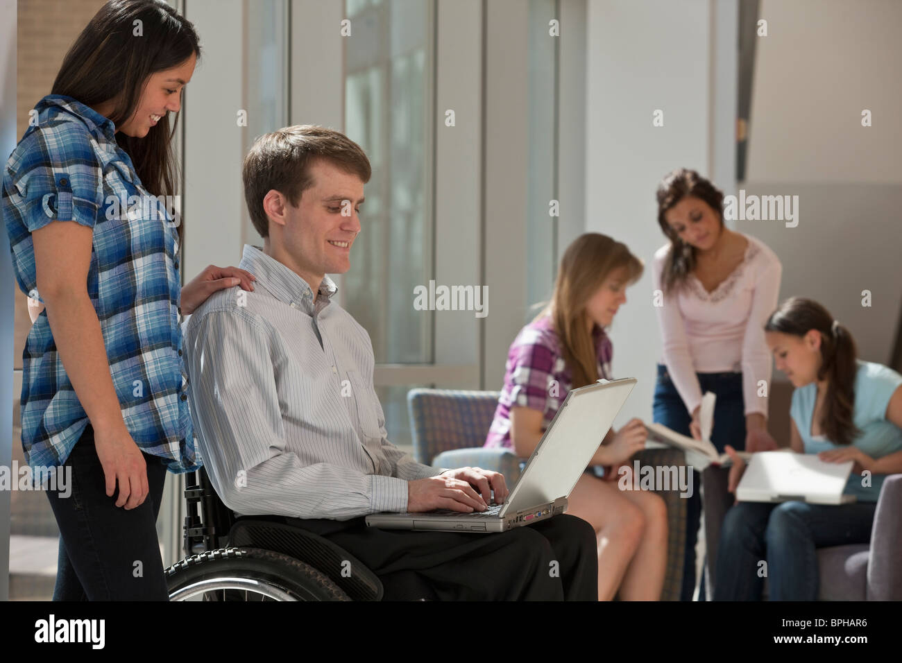 Teacher with spinal cord injury using a laptop with students Stock ...