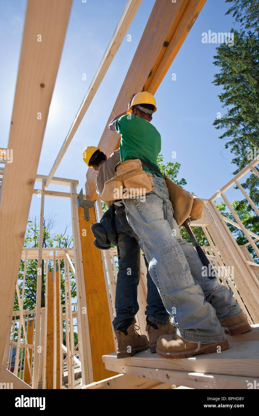 Carpenters lifting a laminated beam at a construction site Stock Photo ...