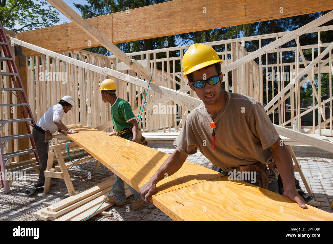 Carpenters lifting a laminated beam at a construction site Stock Photo ...