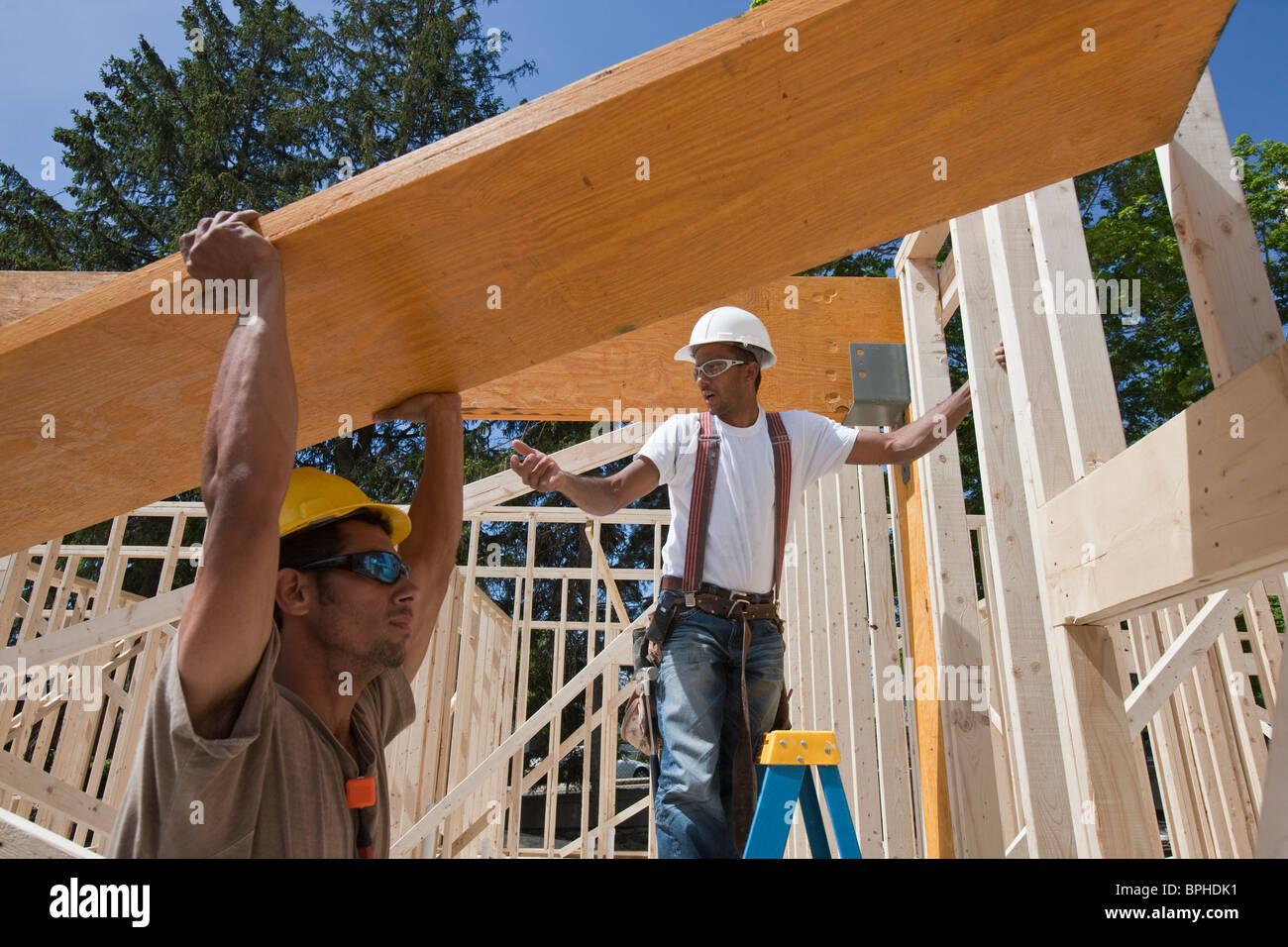 Carpenters lifting a laminated beam at a construction site Stock Photo ...